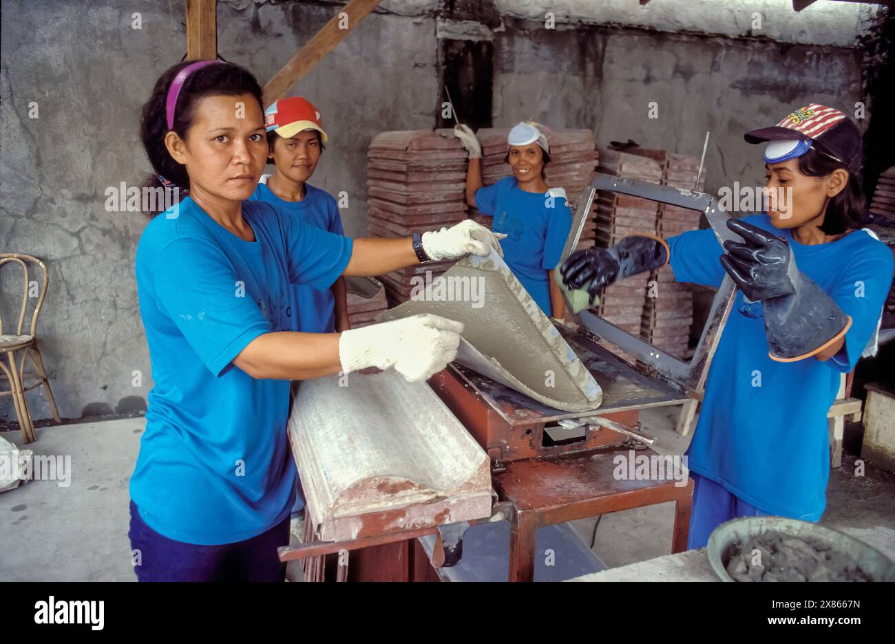 Philippines, Davao Women produce clay roof tiles with a mold at the ...
