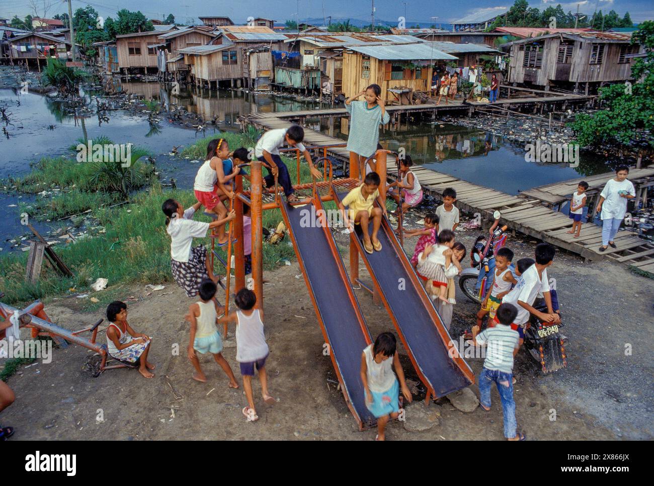Philippines, Mindanao, children on slide at a flooded urban slum in ...