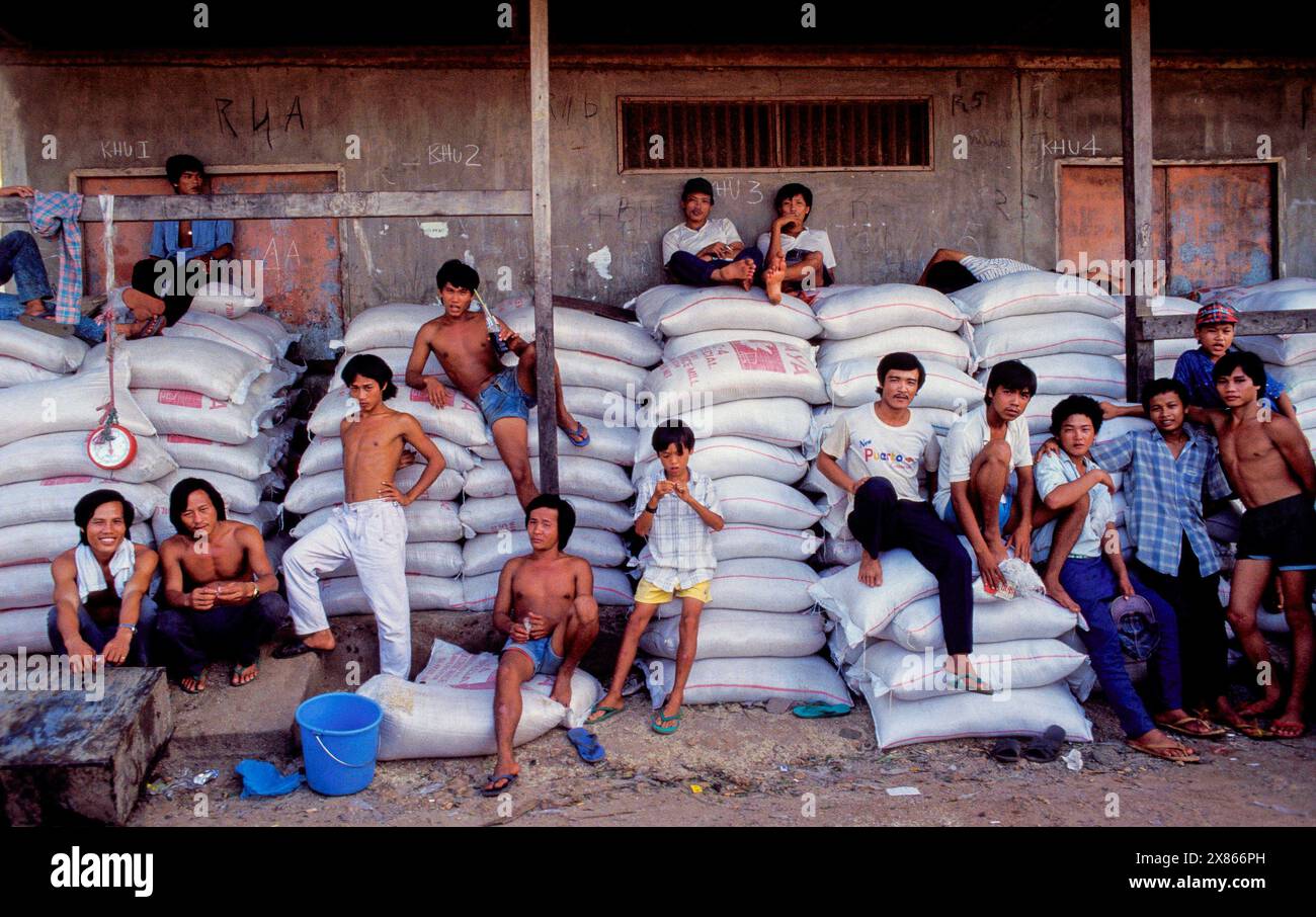 Philippines, Mindanao, workers sit on bags filled with rice flour in a ...