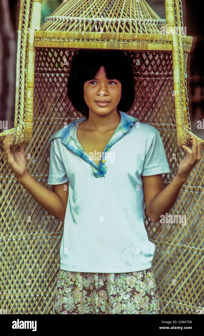 Philippines, Cebu; portrait of a girl carrying a wicker chair she has ...