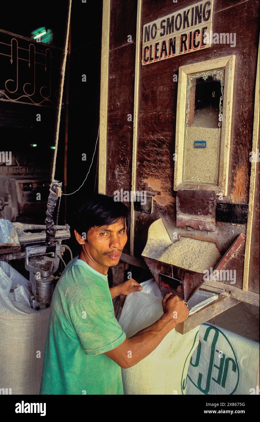 Philippines, Mindanao, Man fills a bag with ground rice flour in a rice ...