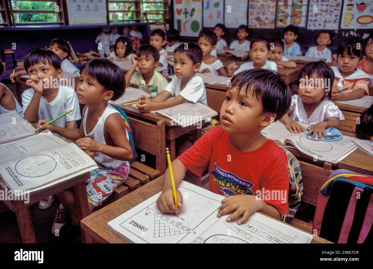 Philippines, Mindanao, Davao; Children listening to their teacher at ...