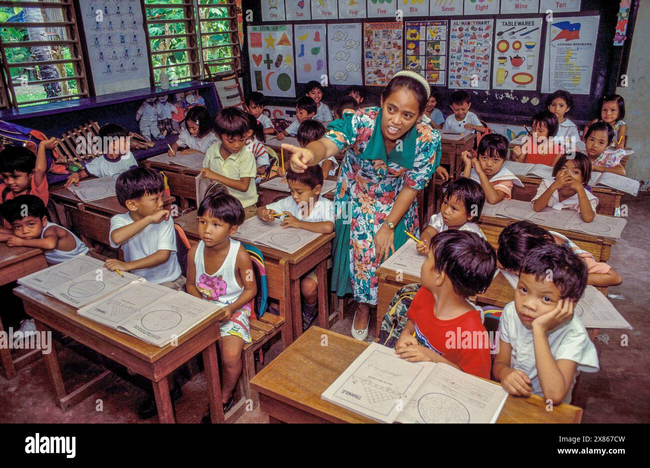 Philippines, Mindanao, Davao; Teacher gives instruction to a child at ...