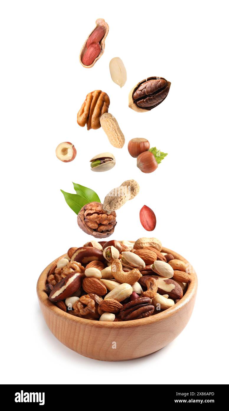 Different nuts falling into bowl on white background Stock Photo - Alamy