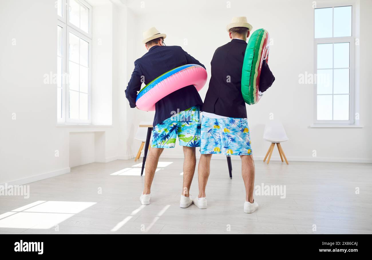Funny coworkers having fun standing back in office with rubber rings ...