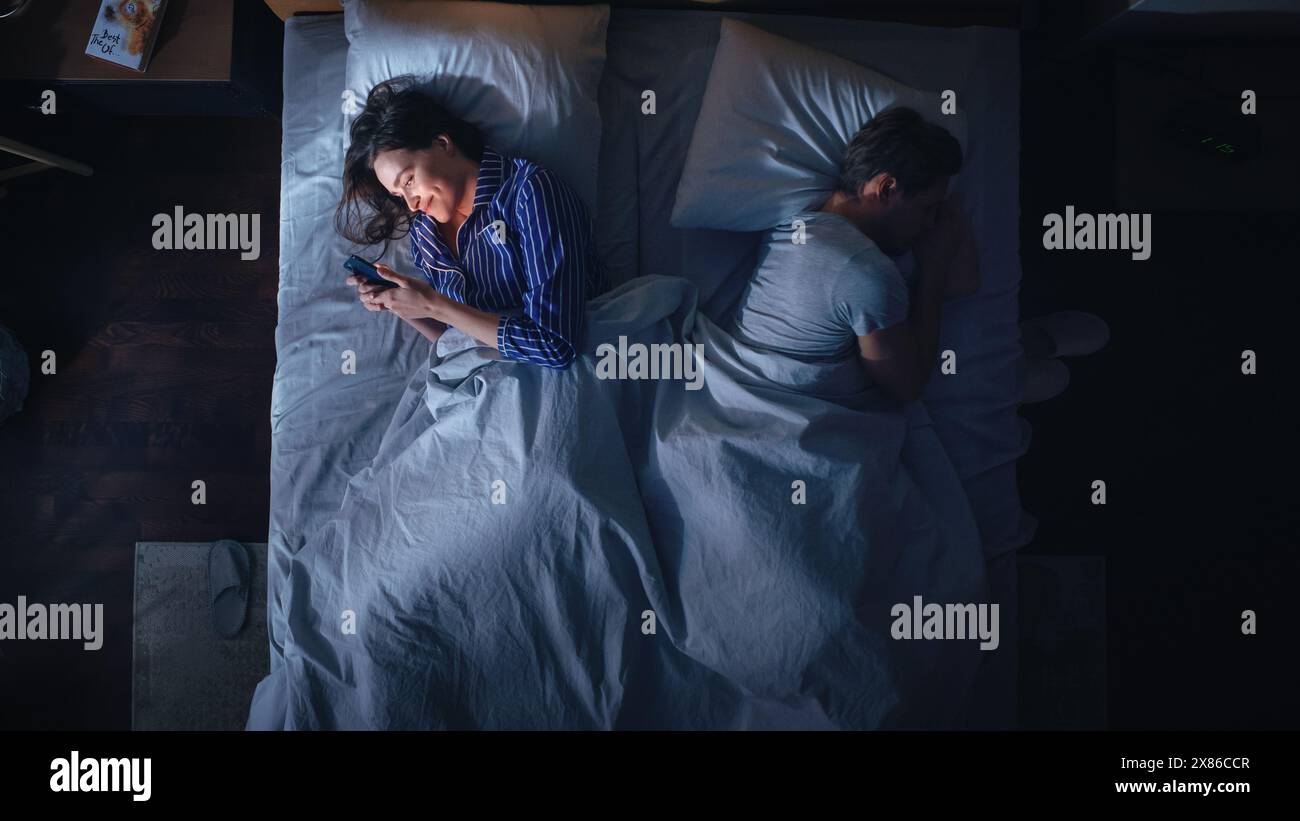Top View: Young Woman Uses Smartphone in Bed at Night When Her Male ...