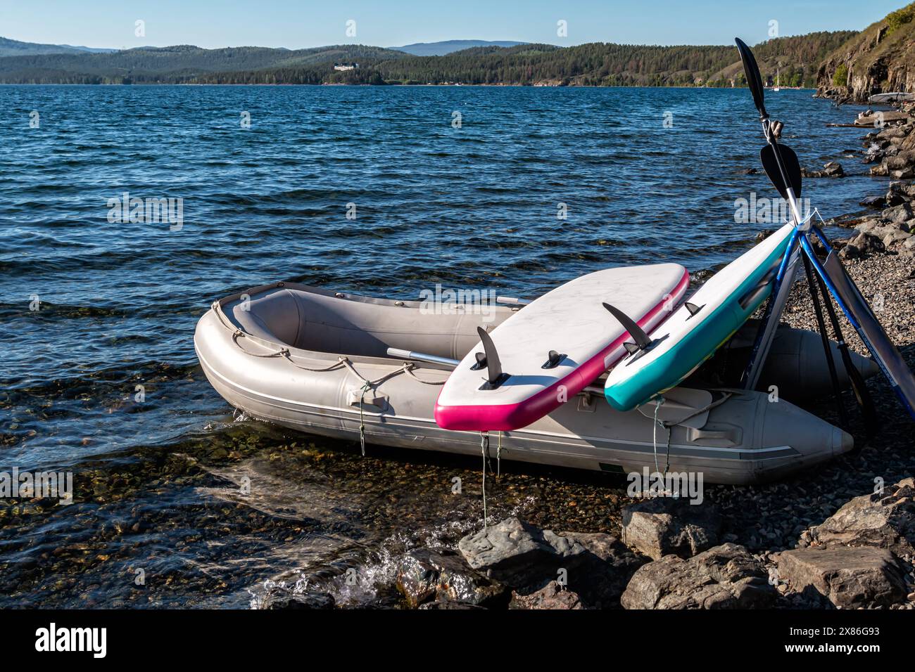 Rubber boat with two SUP boards on a rocky seashore Stock Photo - Alamy
