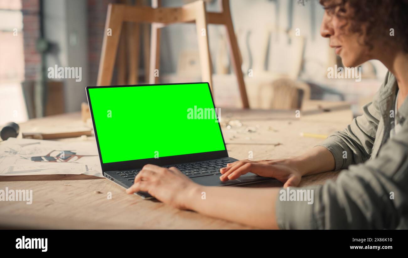 Multiethnic Furniture Designer Working on Laptop Computer with Green Screen Mock Up Display ...
