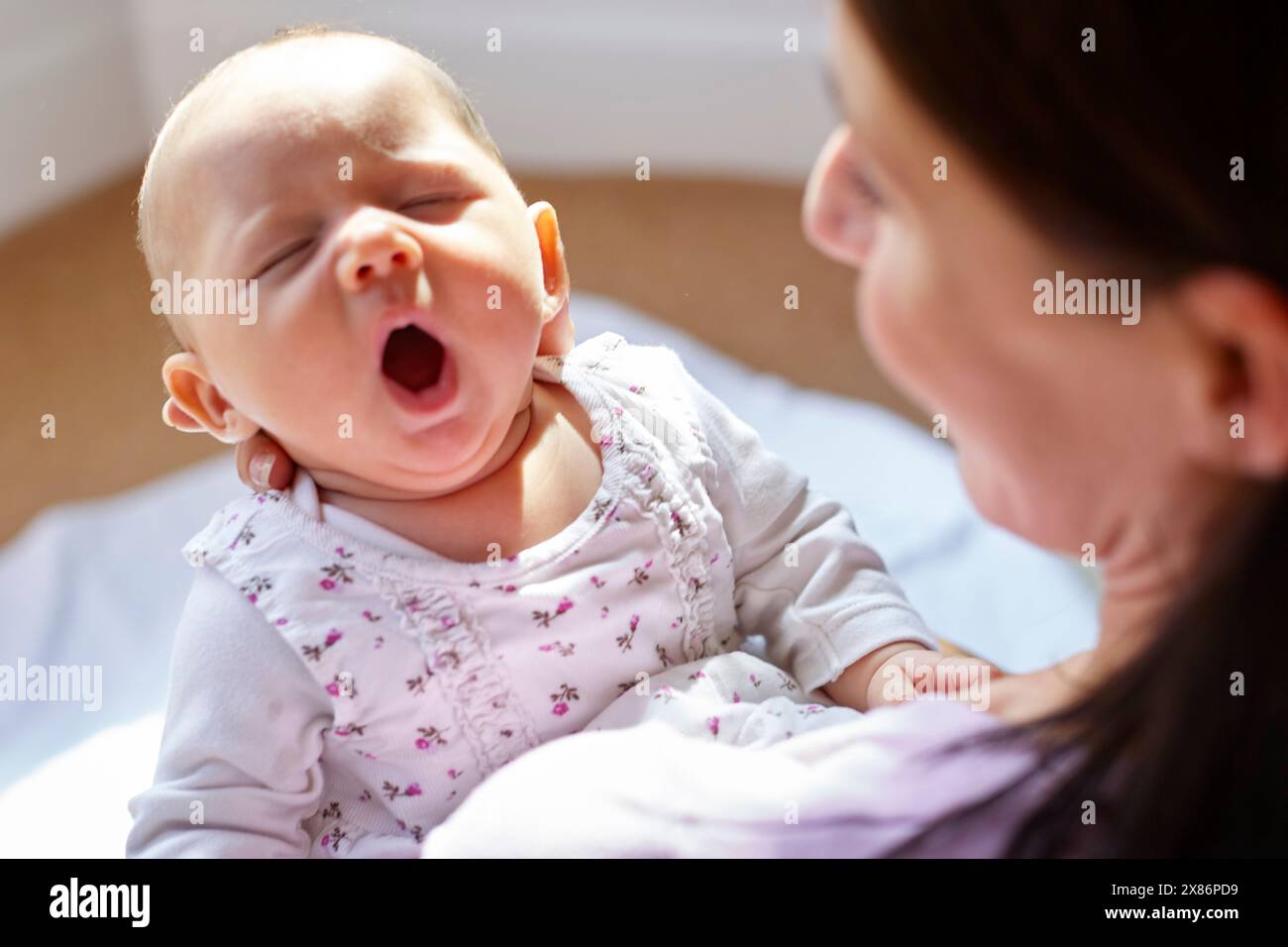 Mother holding yawning baby Stock Photo - Alamy