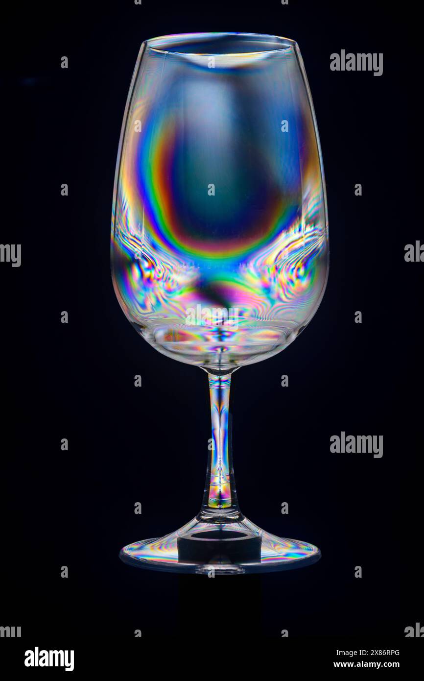 Transparent clear plastic wine glass viewed between crossed polarising ...