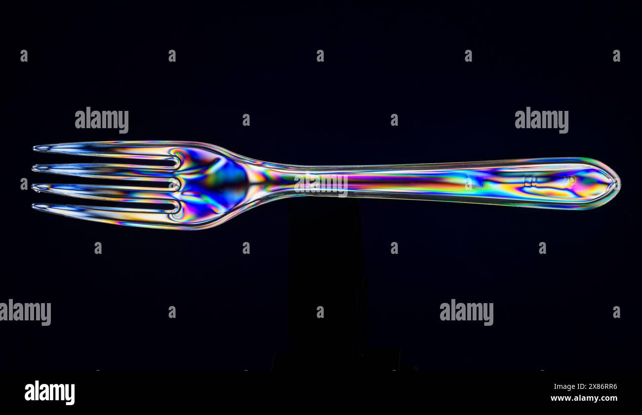 A clear plastic fork viewed between crossed polarising filters Stock ...