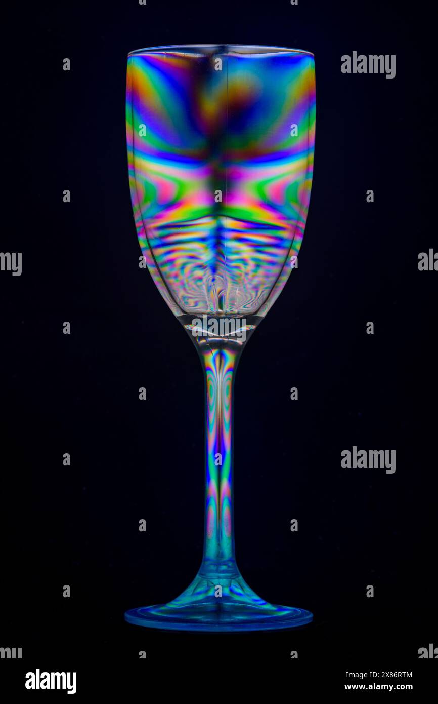 Transparent clear plastic wine glass viewed between crossed polarising ...