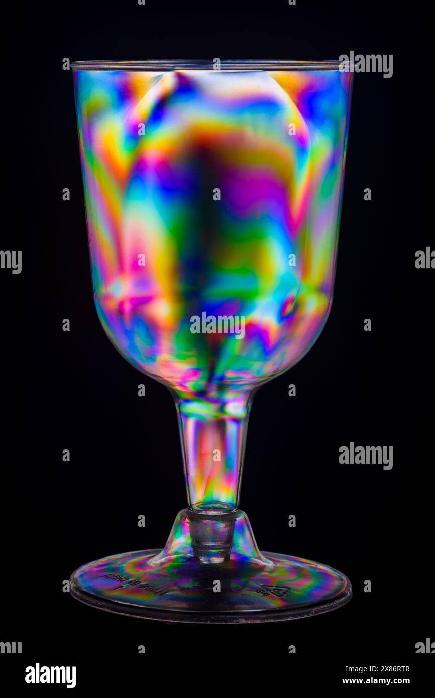 Transparent clear plastic wine glass viewed between crossed polarising ...