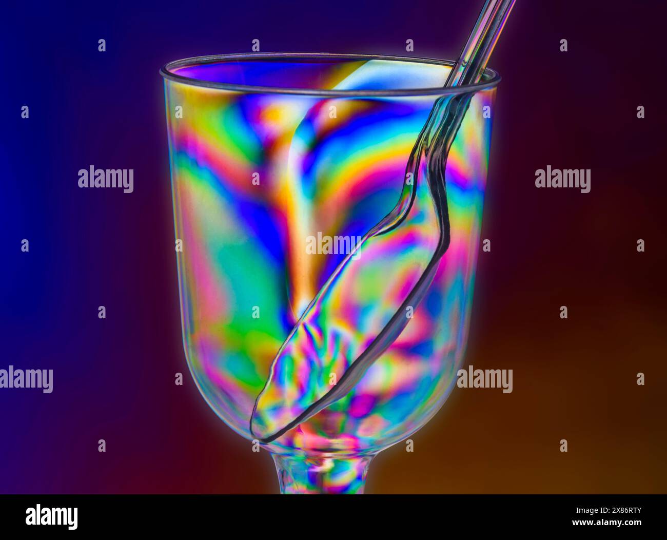 Transparent clear plastic wine glass and spoon viewed between crossed ...