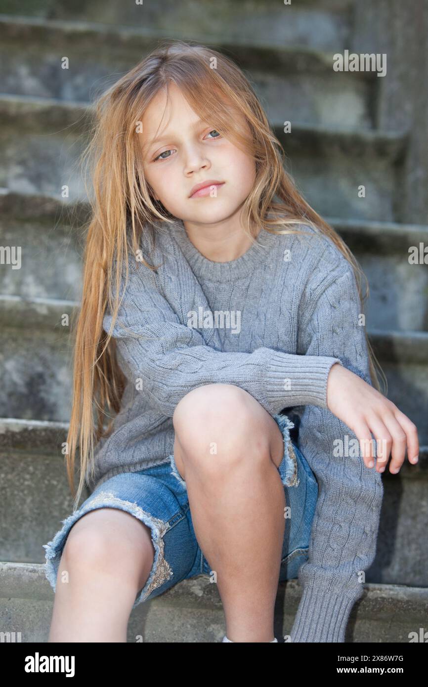 sad little girl sitting on stairs Stock Photo - Alamy