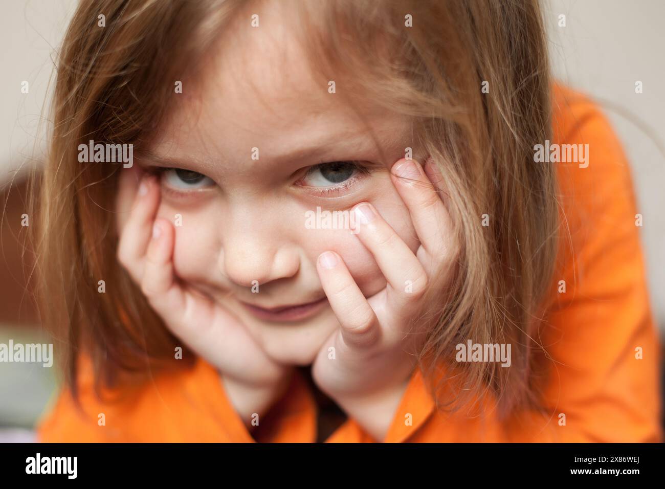 cute little girl look under her eyebrows resting her head on hands ...