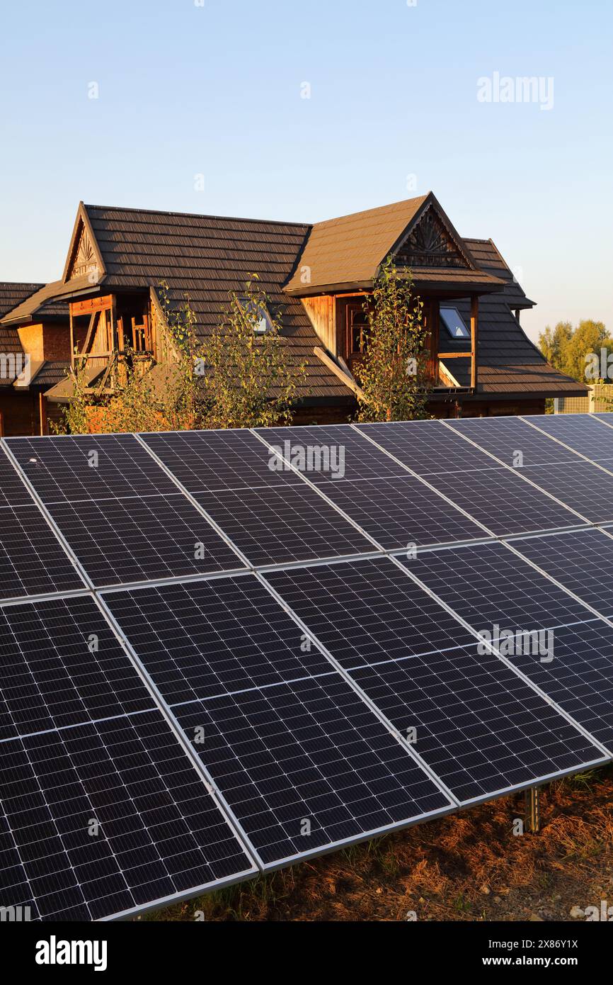 Solar panels mounted on frame in next to a traditional mountain house ...