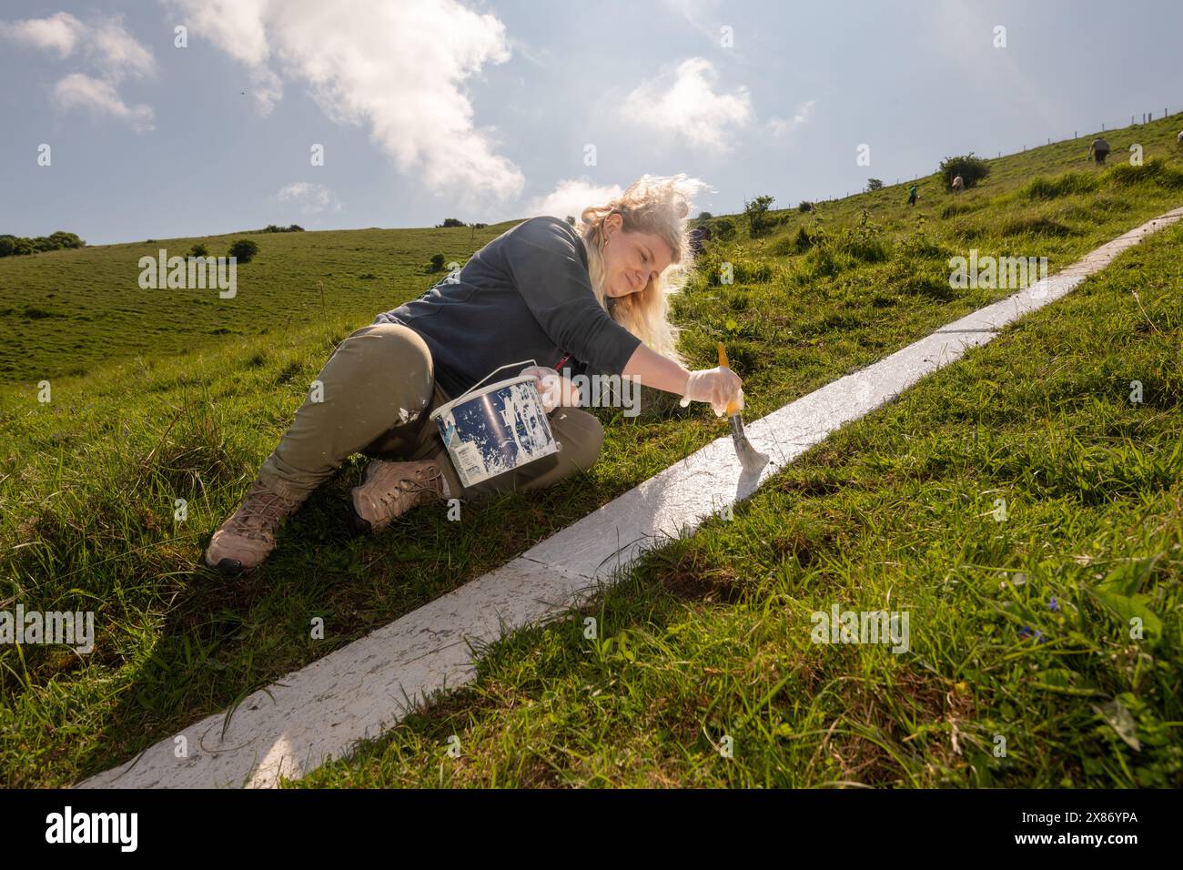 Wilmington, East Sussex, UK, 23/05/2024, Katie Pearce helps paint the ...