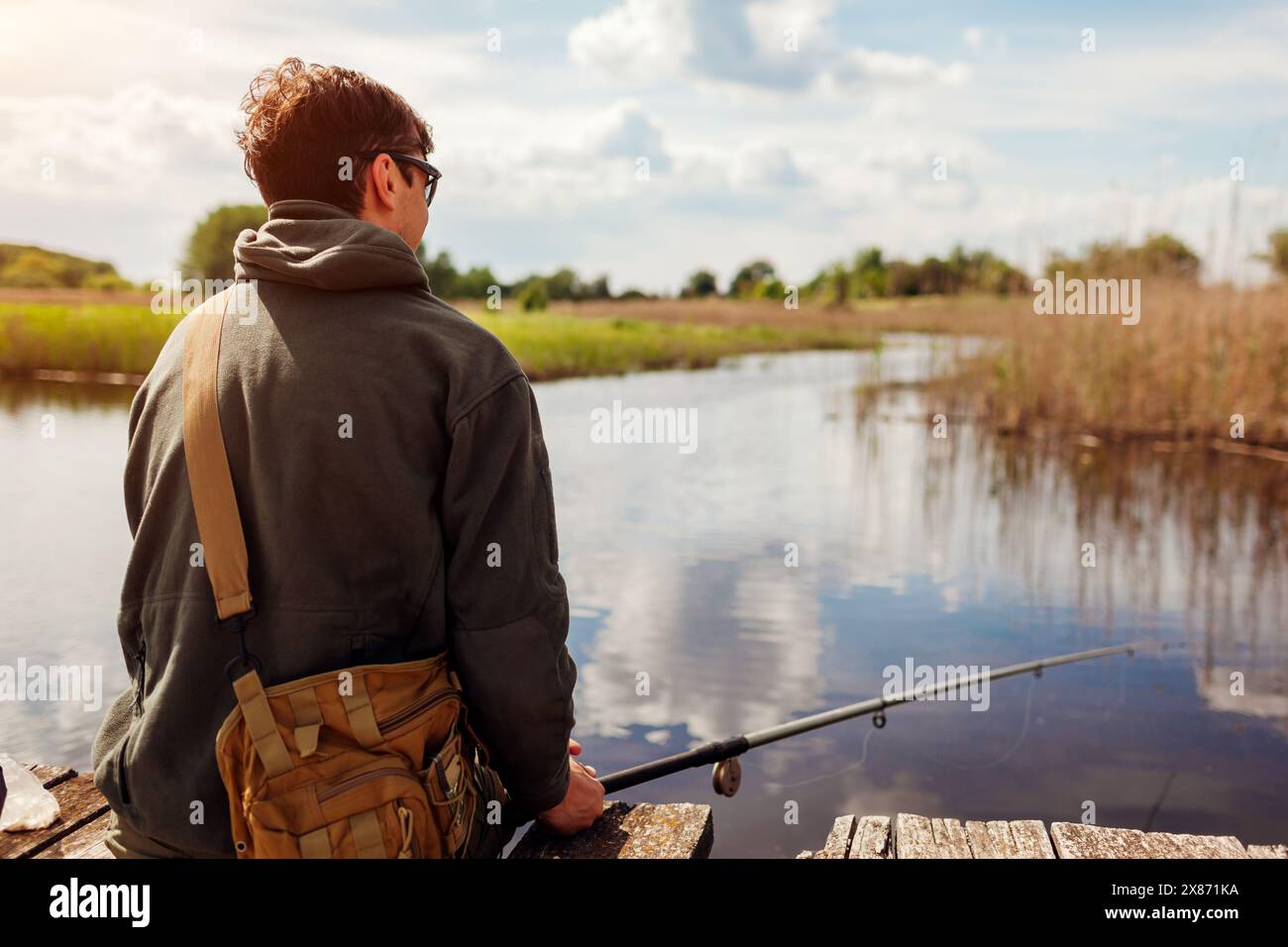 Back view of man fishing wearing military uniform. Fisherman sitting on ...