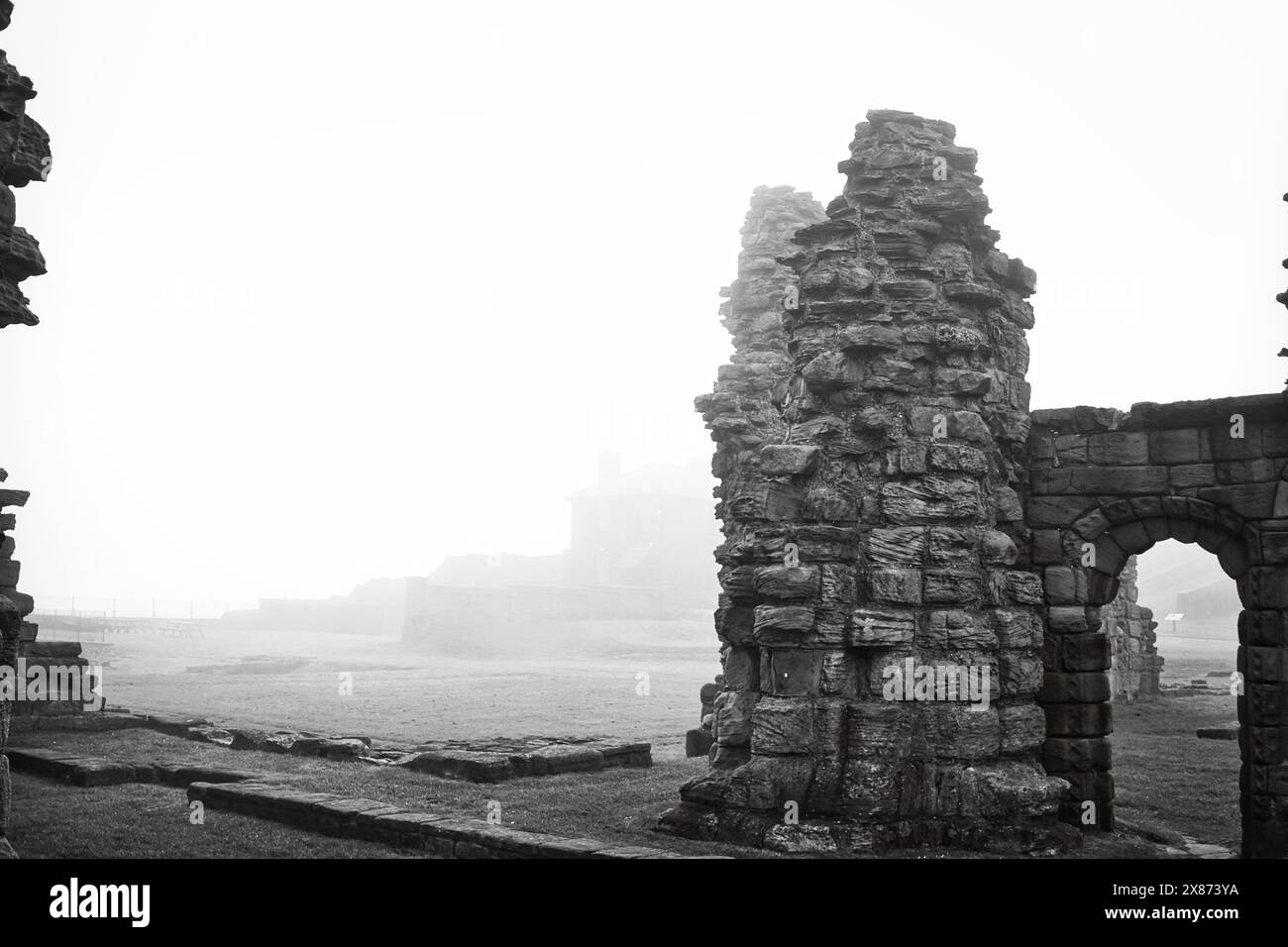 Black and white photograph of ancient stone ruins shrouded in fog. The ...