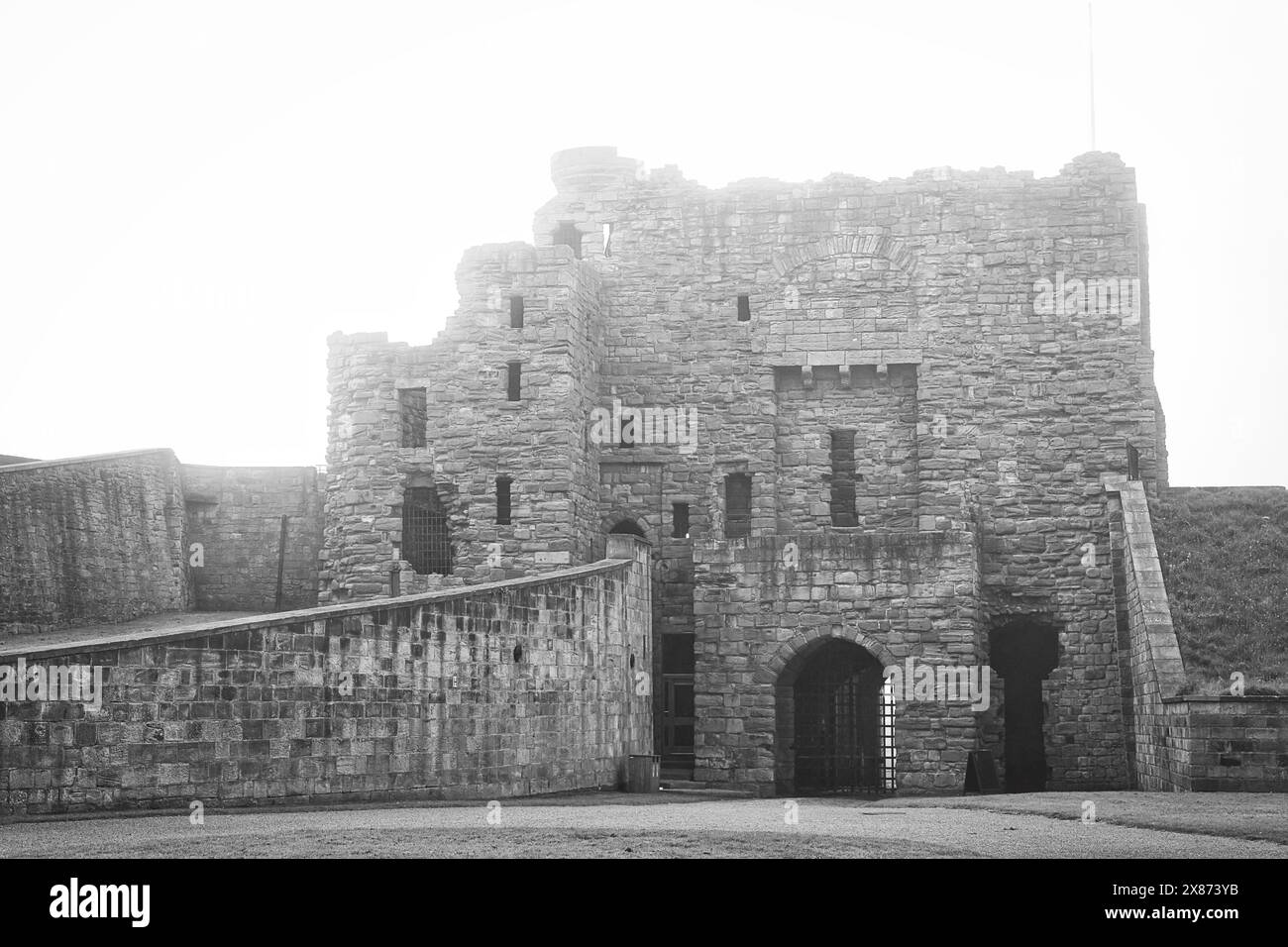A black and white photograph of an old stone castle with a partially ...