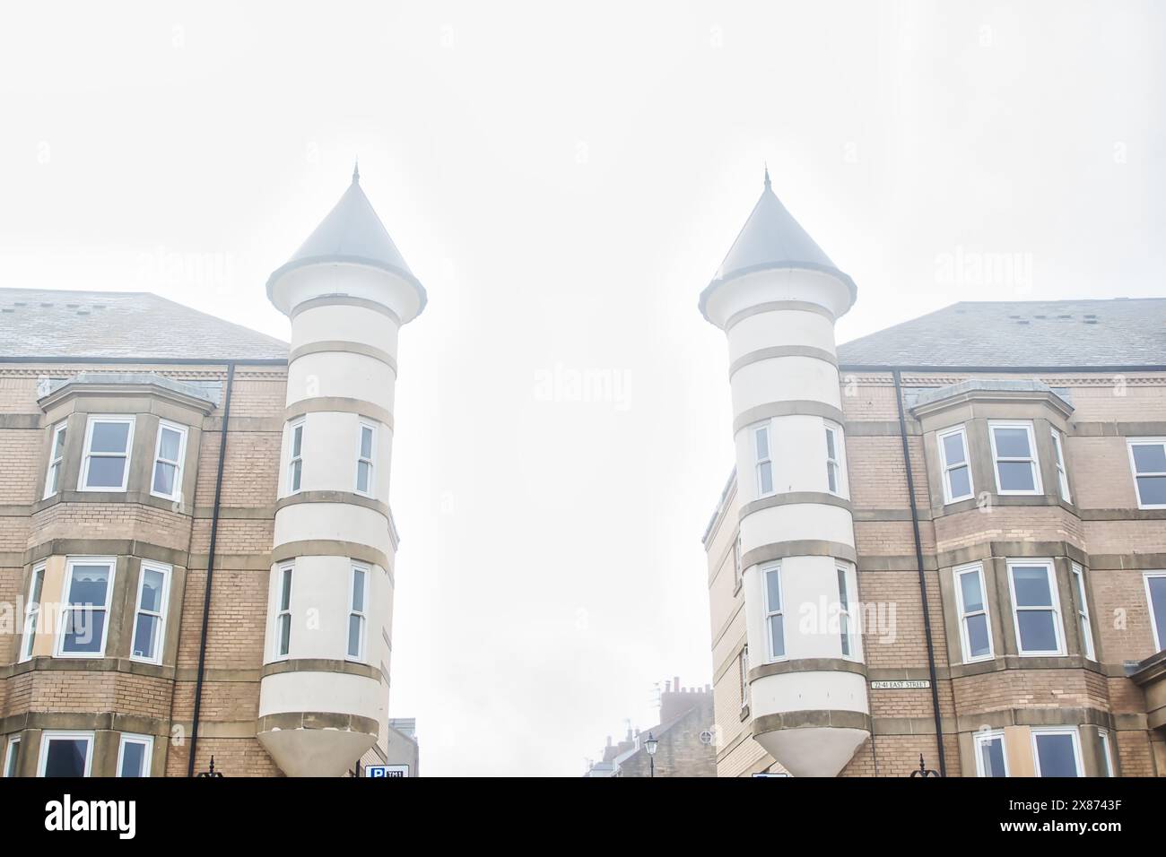 Two symmetrical brick buildings with cylindrical towers and conical ...