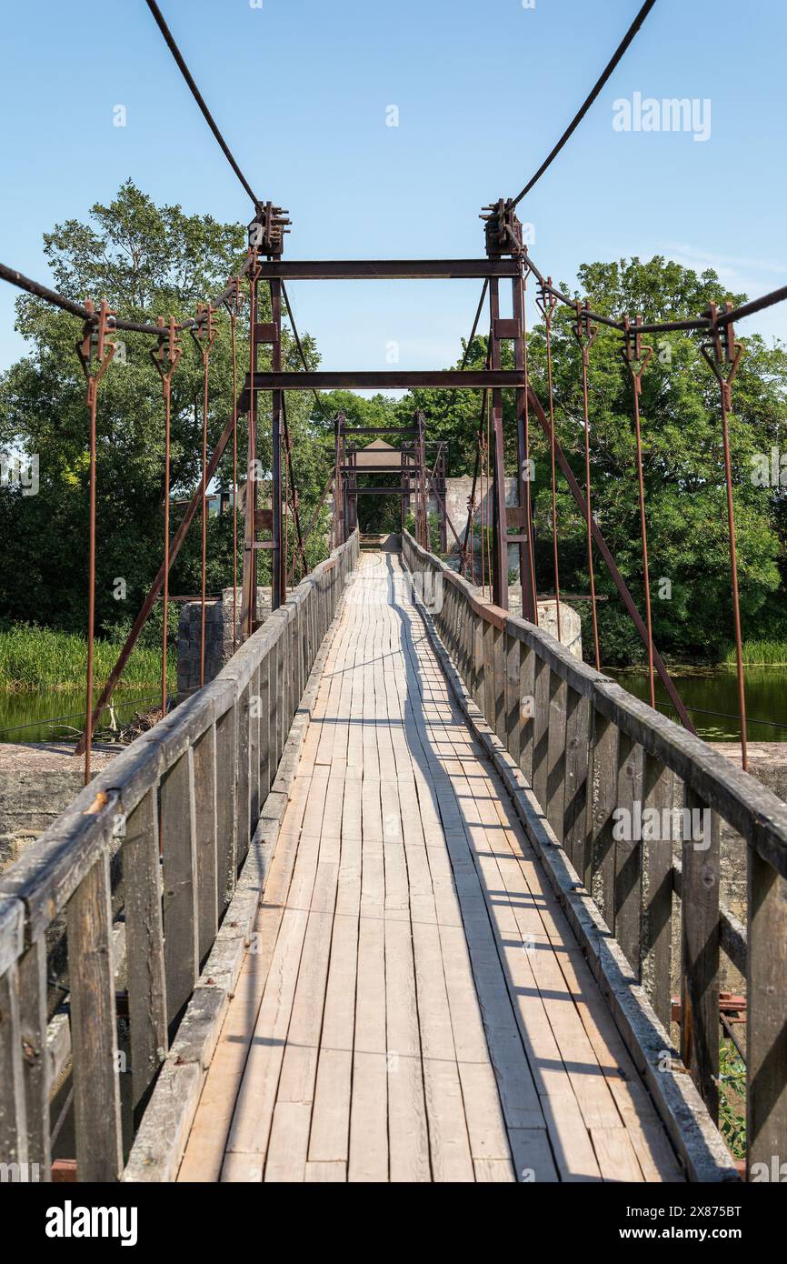 A long suspension pedestrian bridge with rusted metal structures in ...