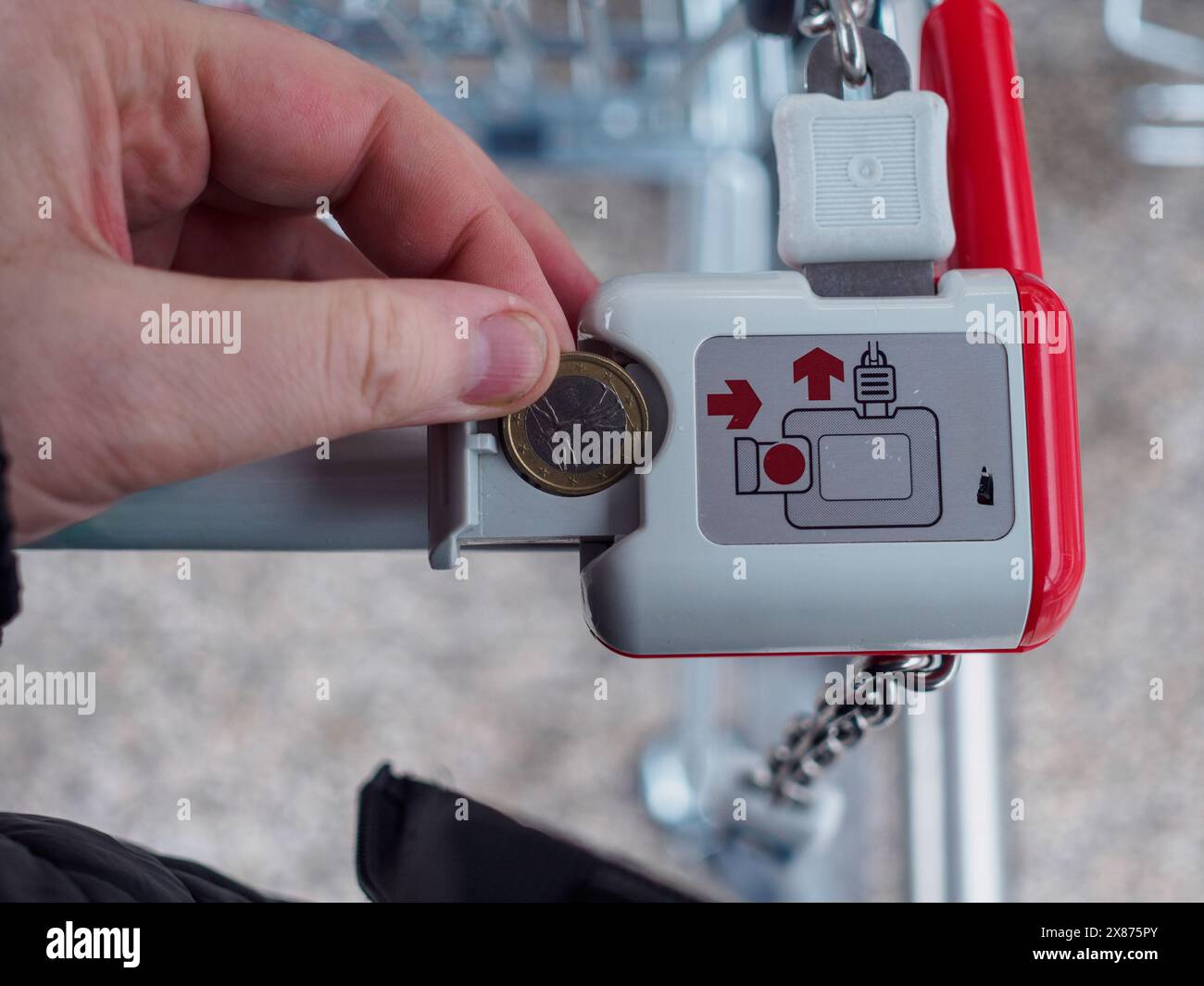Closeup view of a person inserting a coin into a shopping cart lock ...