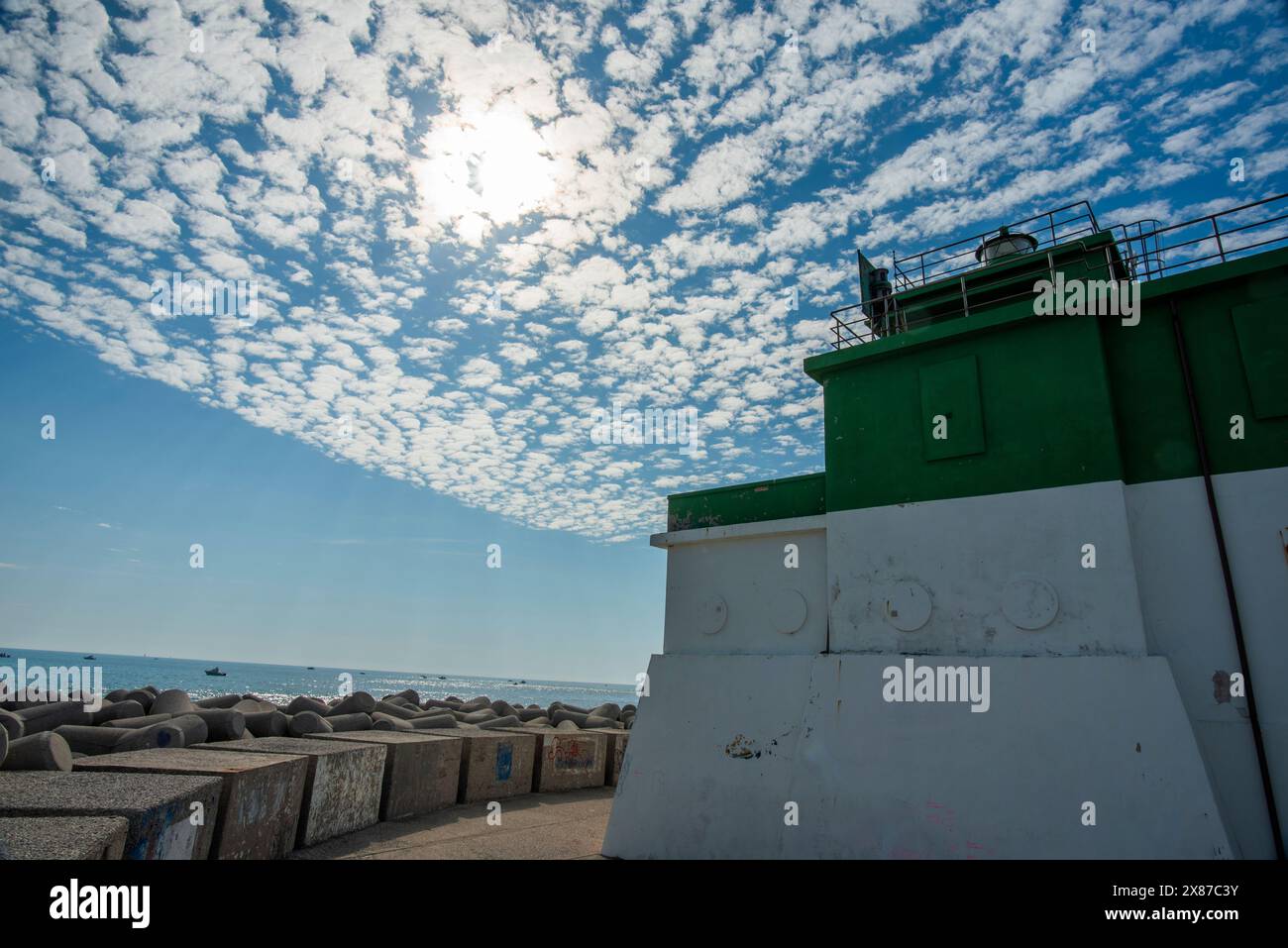 green lighthouse of Malamocco harbor inlet with concrete breakwaters ...