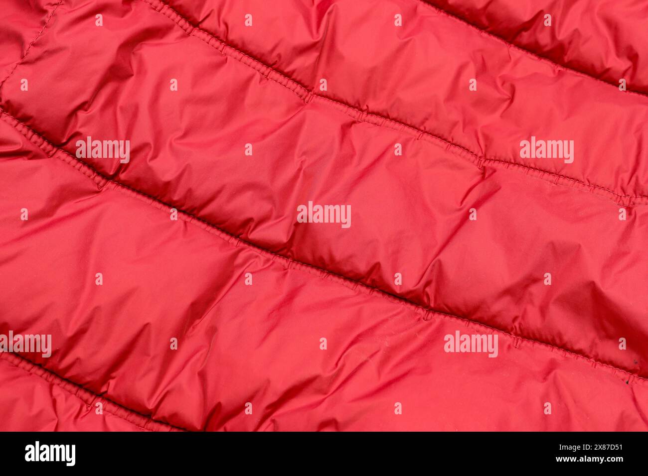 Red waterproof winter puffer jacket close up. Polyester fabric textile ...