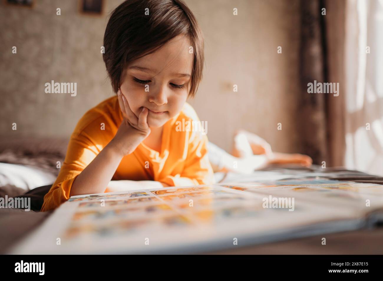 Cute boy reading book on bed at home Stock Photo - Alamy