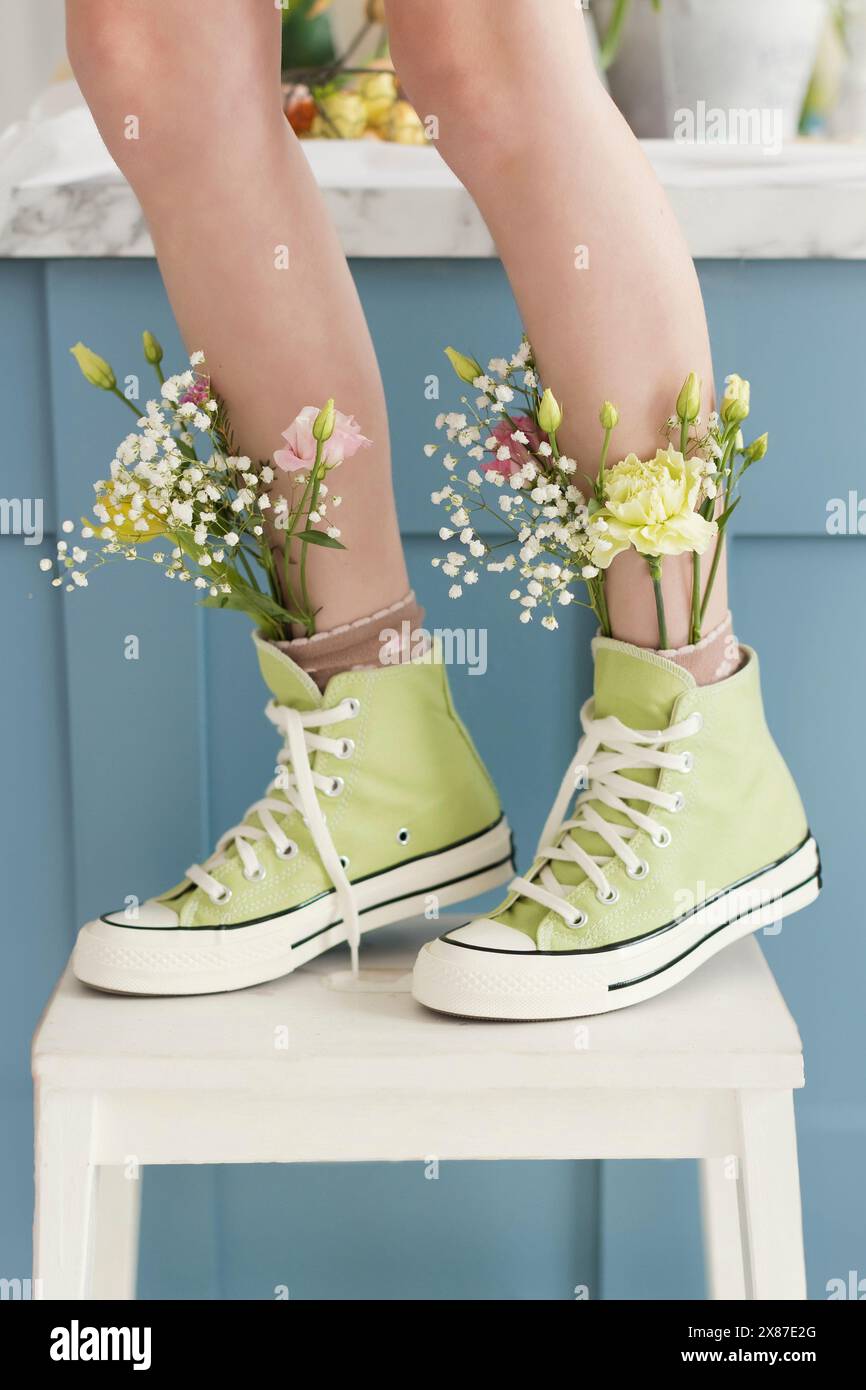 Girl standing on stool wearing green shoes with flowers Stock Photo - Alamy
