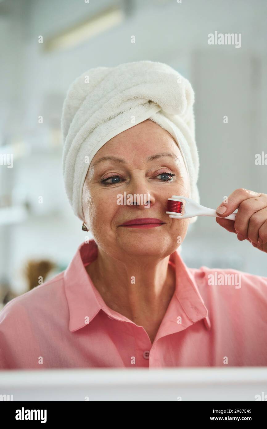 Senior woman using face roller hi-res stock photography and images - Alamy