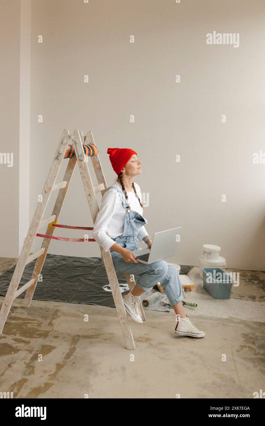 Woman with laptop sitting on ladder in new home Stock Photo - Alamy