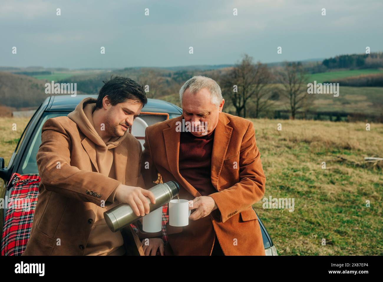 Man pouring tea in cups with father on mountain Stock Photo - Alamy