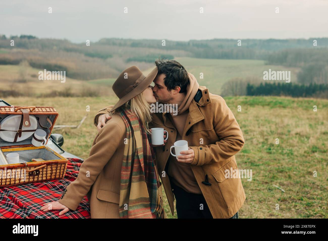 Romantic couple kissing each other and holding tea cups on picnic Stock ...