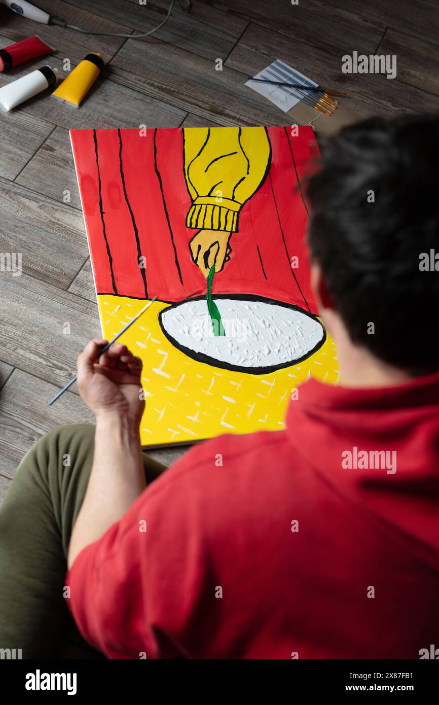 Painter holding brush near painting on floor at home Stock Photo - Alamy