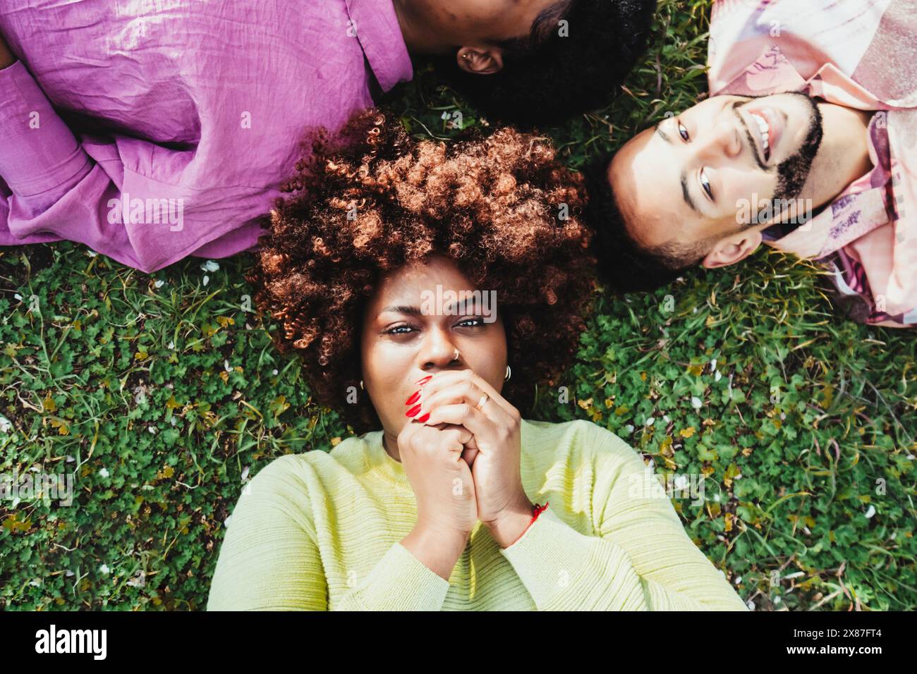 Afro woman lying down on grass with friends at park Stock Photo - Alamy