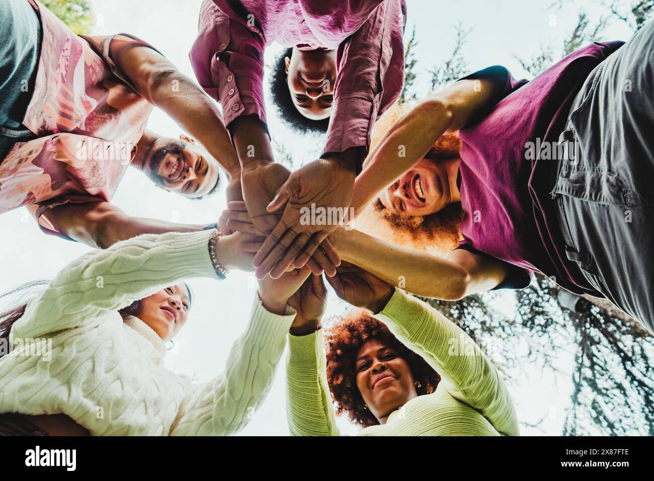 Multiracial friends stacking hands at park Stock Photo - Alamy