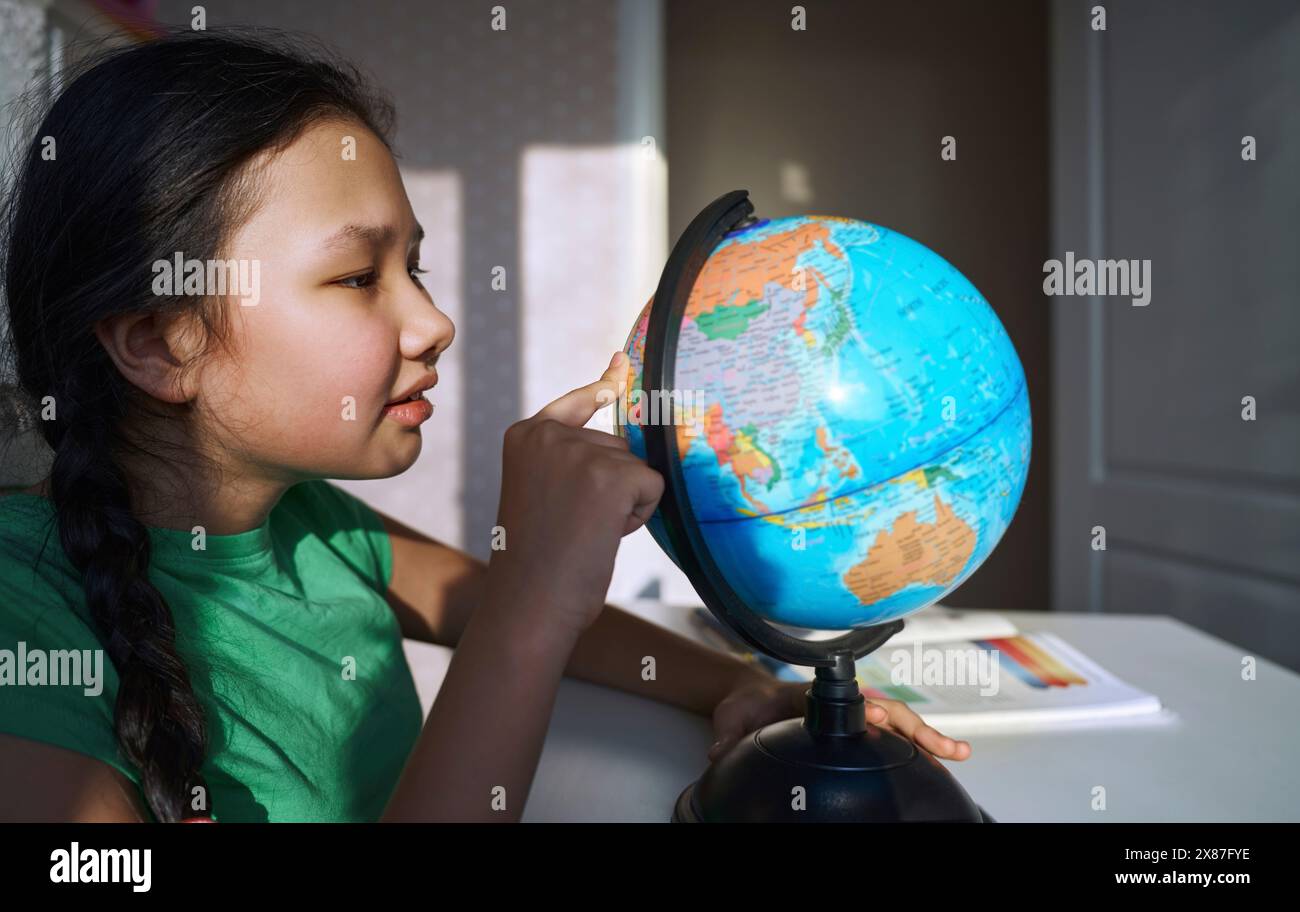 Girl learning geography using globe at home Stock Photo - Alamy