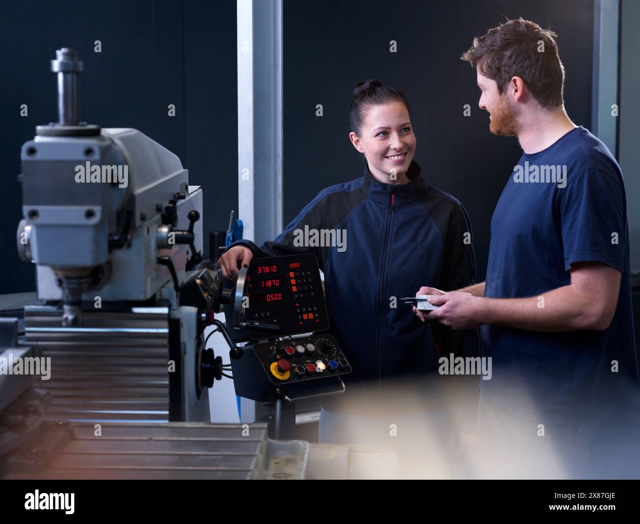 Engineers working on CNC machine at factory Stock Photo - Alamy