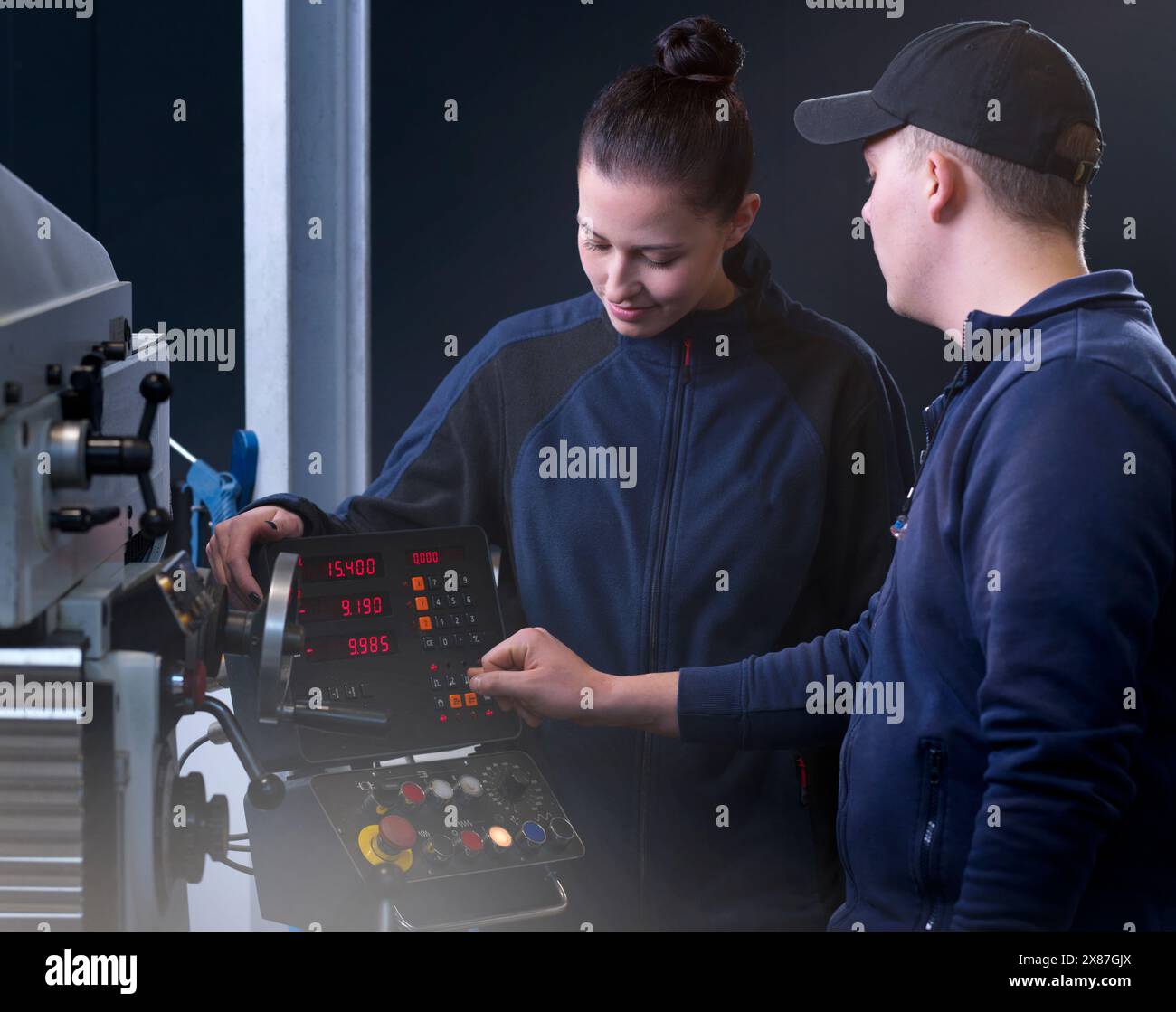 Engineers operating CNC machine at factory Stock Photo - Alamy