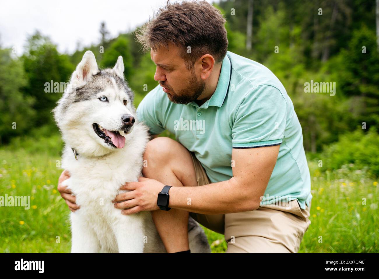 Mature man kneeling by Husky dog Stock Photo - Alamy