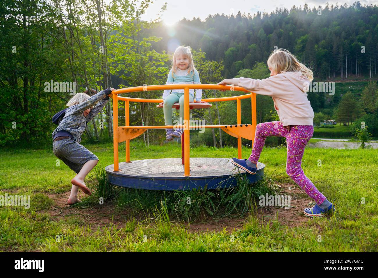 Siblings spinning and enjoying carousel at playground Stock Photo - Alamy