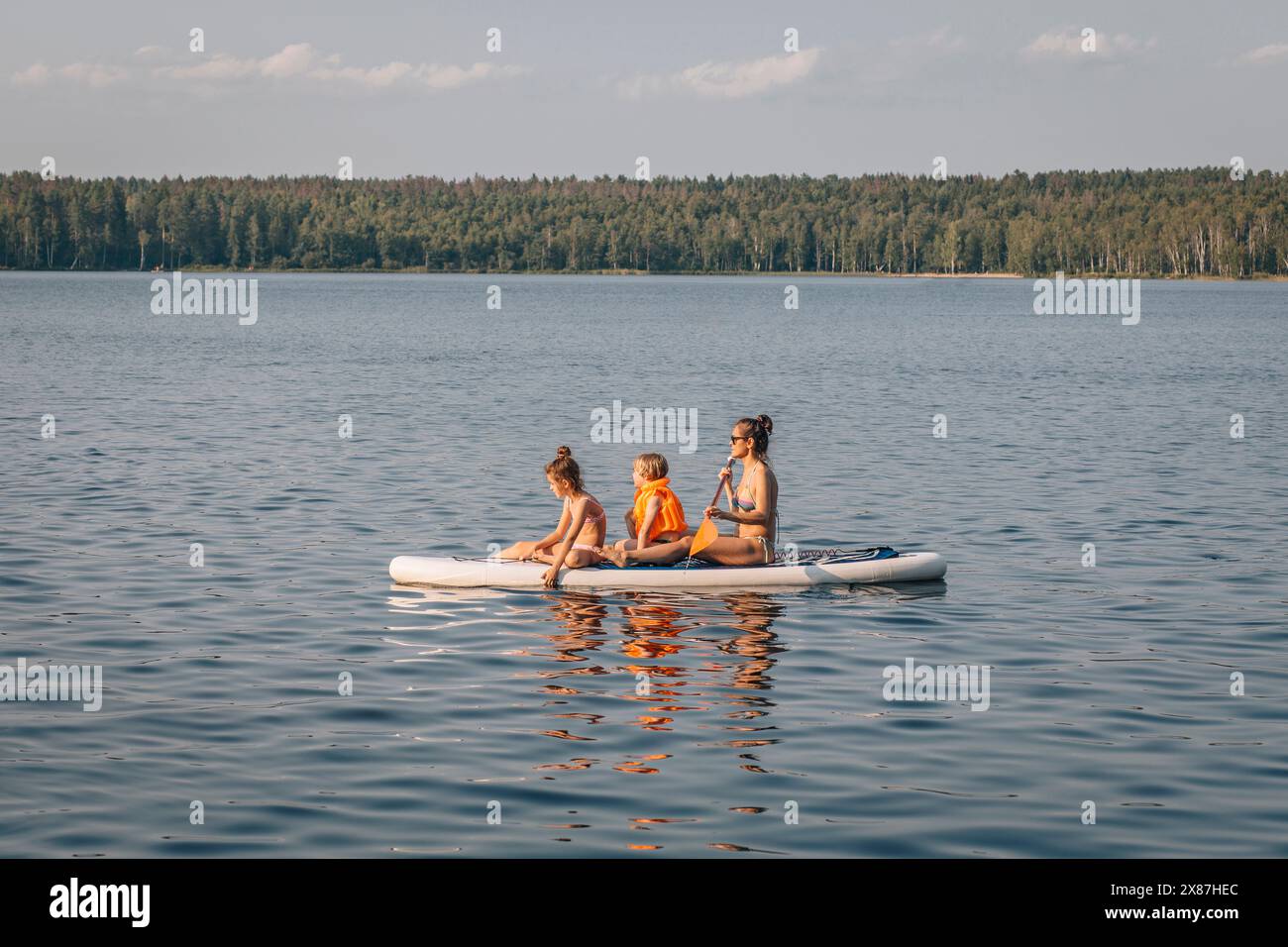 Mother with children paddleboarding in sea Stock Photo - Alamy