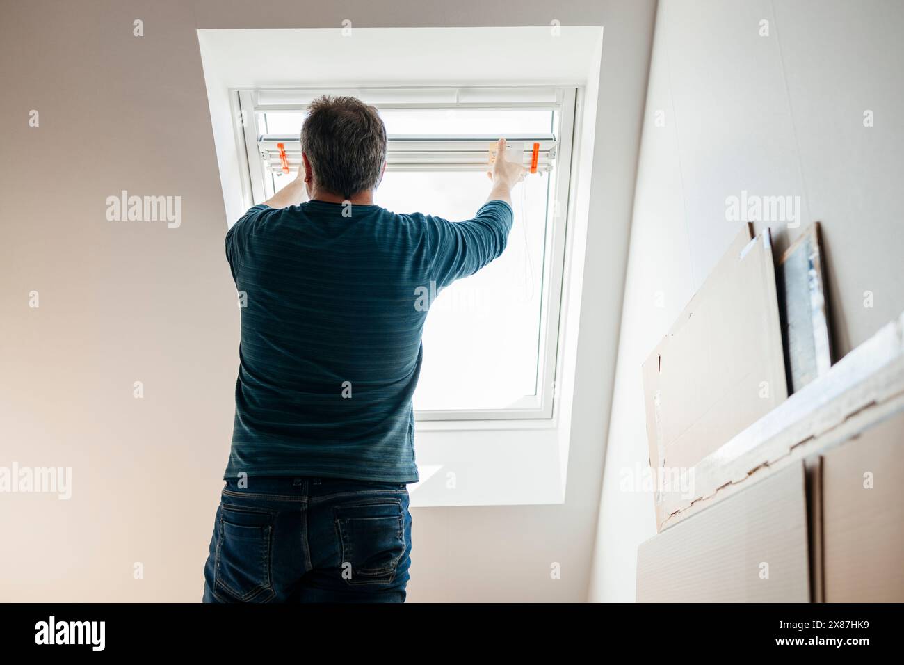 Man installing blinds on attic window at home Stock Photo - Alamy
