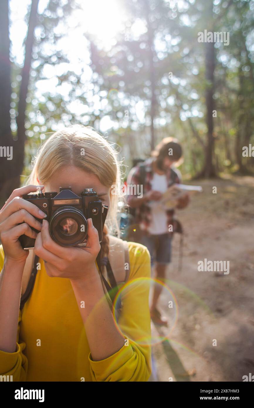 Blond woman clicking pictures through camera in forest Stock Photo - Alamy