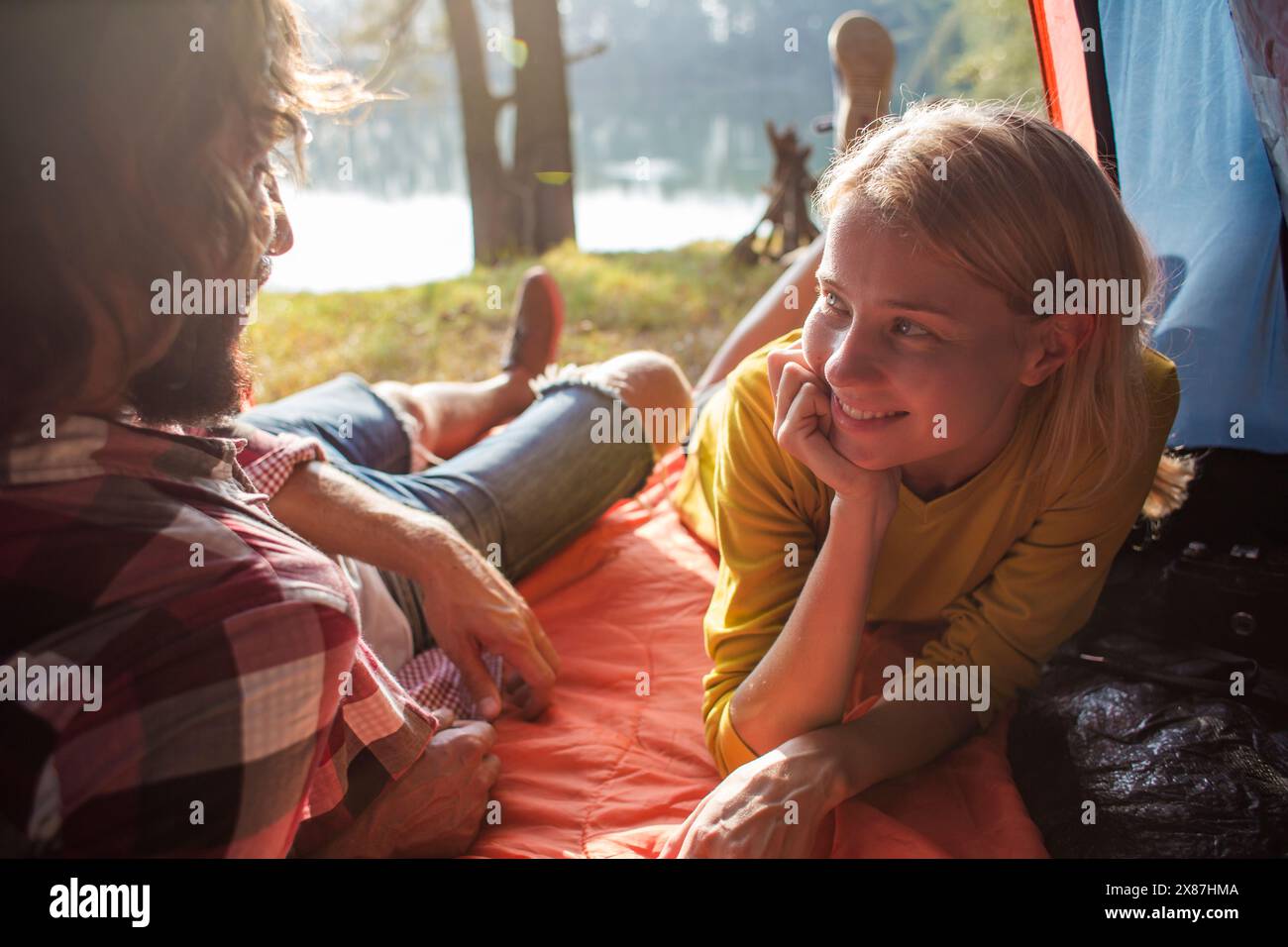 Smiling woman lying next to boyfriend in tent Stock Photo - Alamy