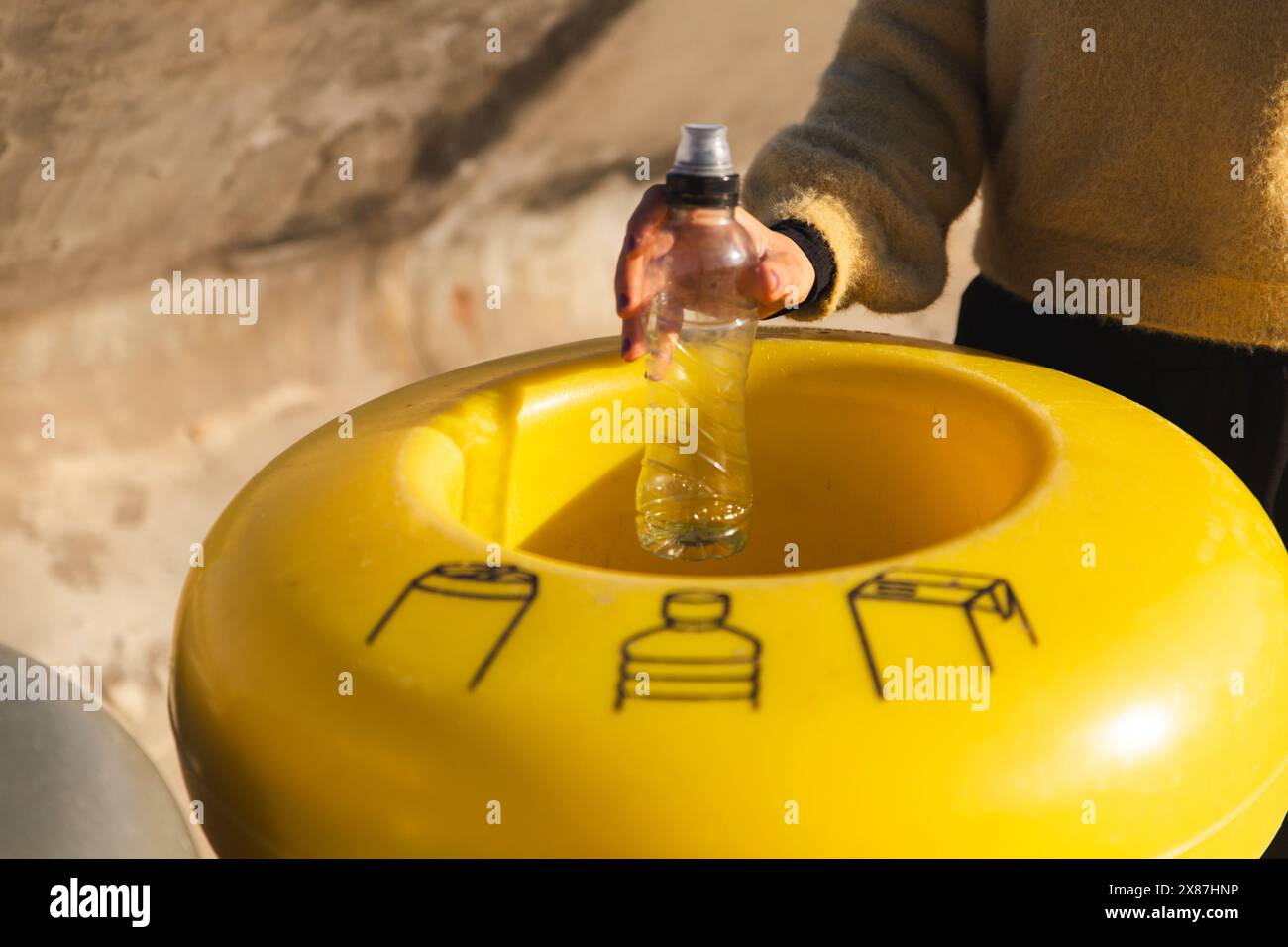 Woman throwing plastic bottle into yellow bin Stock Photo - Alamy