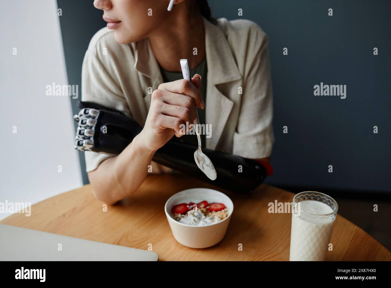 Young woman with bionic hand eating breakfast at table Stock Photo - Alamy